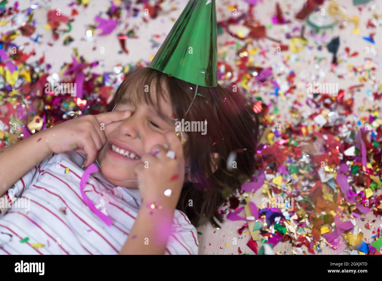 Happy kid celebrating party with blowing confetti while lying on the ...