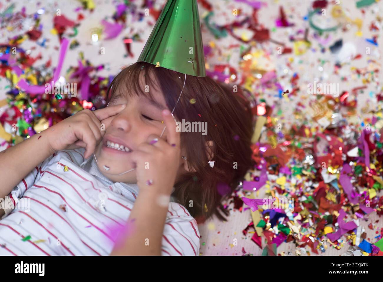 Happy kid celebrating party with blowing confetti while lying on the ...