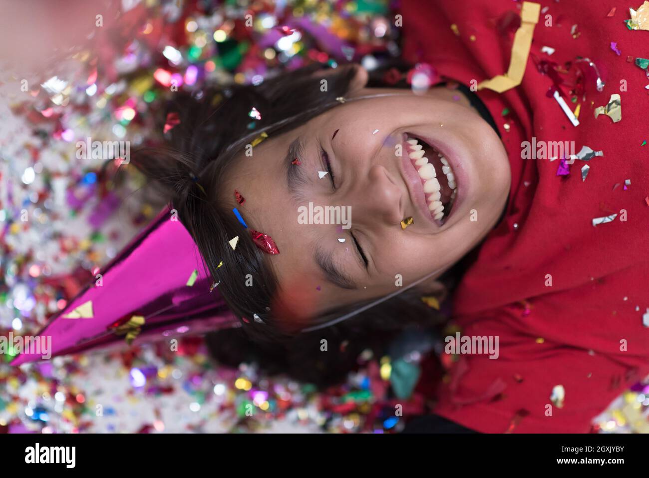 Happy kid celebrating party with blowing confetti while lying on the ...
