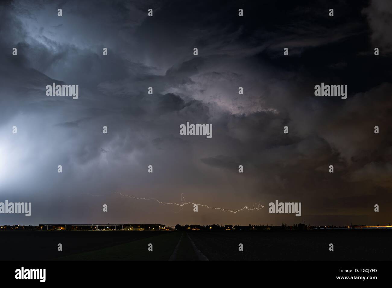 Storm cloud at night with orange colored horizontal lightning discharge ...