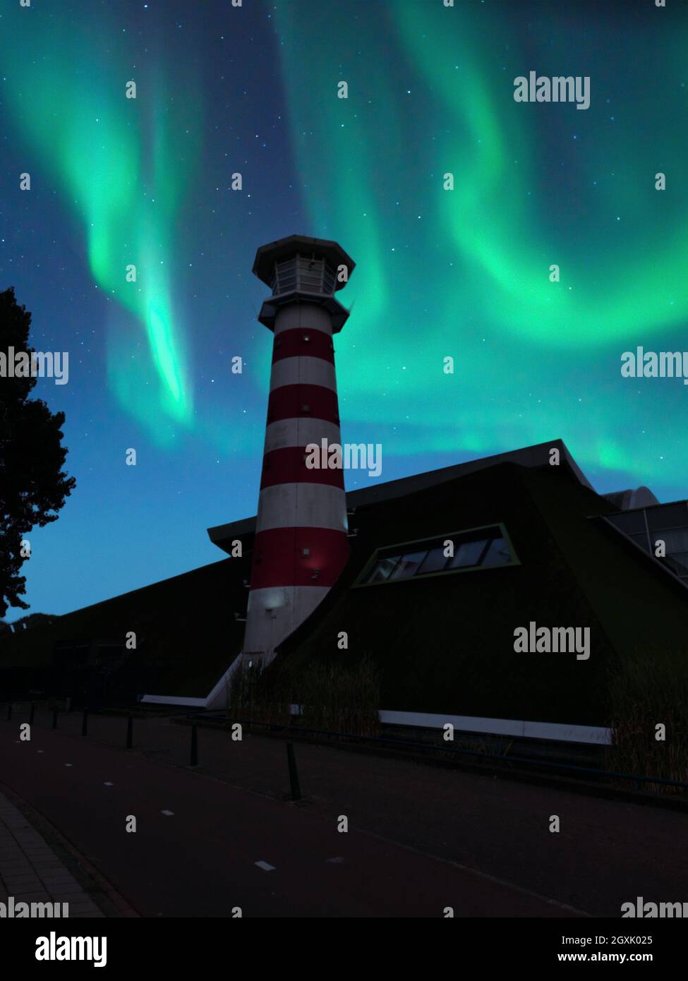 Green colored northern lights, also known as aurora, above a lighthouse ...