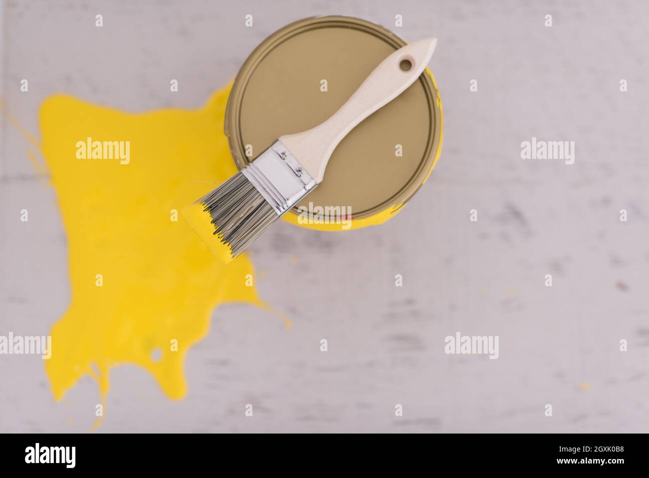 Yellow paint tin can with brush on top with yellow strokes on the ...