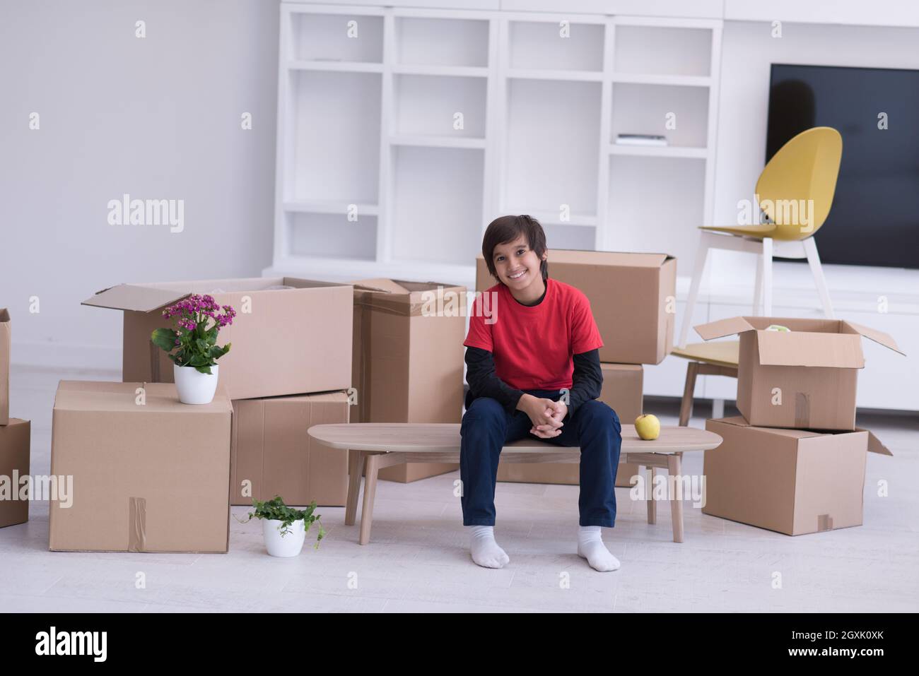 happy little boy sitting on the table with cardboard boxes around him ...
