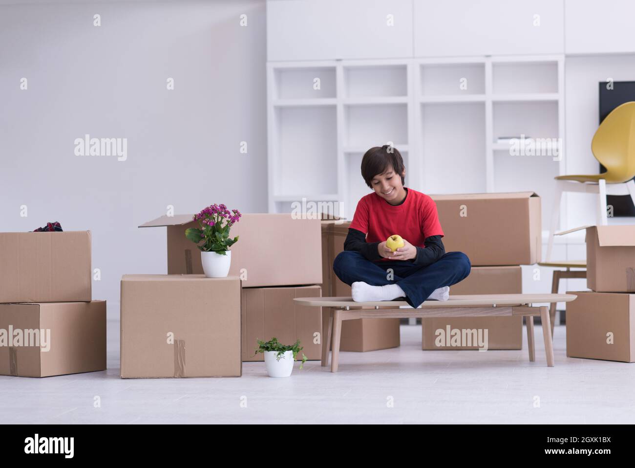 happy little boy sitting on the table with cardboard boxes around him ...