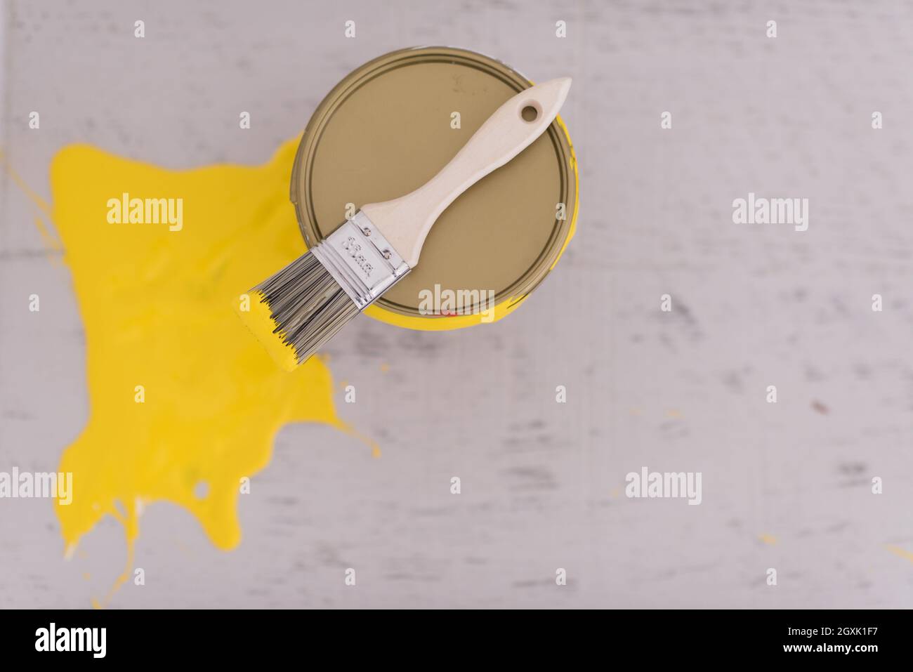 Yellow paint tin can with brush on top with yellow strokes on the ...