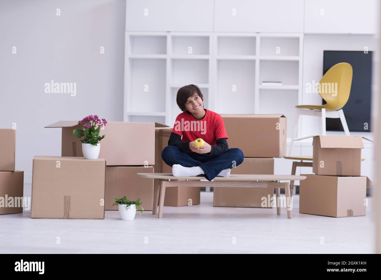 happy little boy sitting on the table with cardboard boxes around him ...