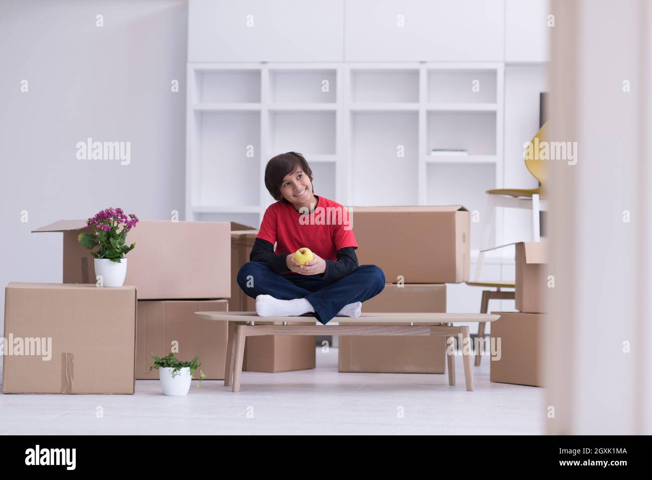 happy little boy sitting on the table with cardboard boxes around him ...