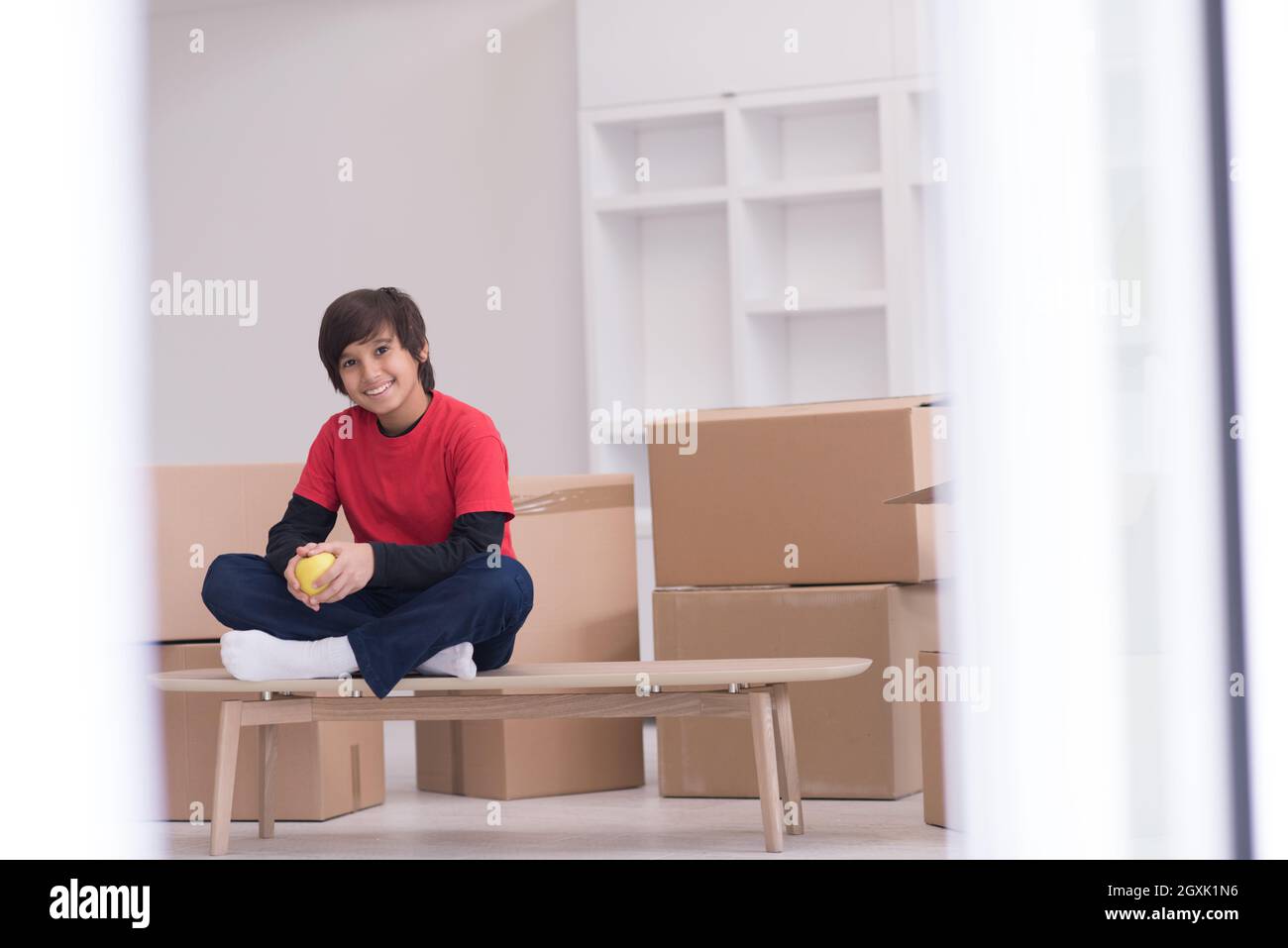 happy little boy sitting on the table with cardboard boxes around him ...