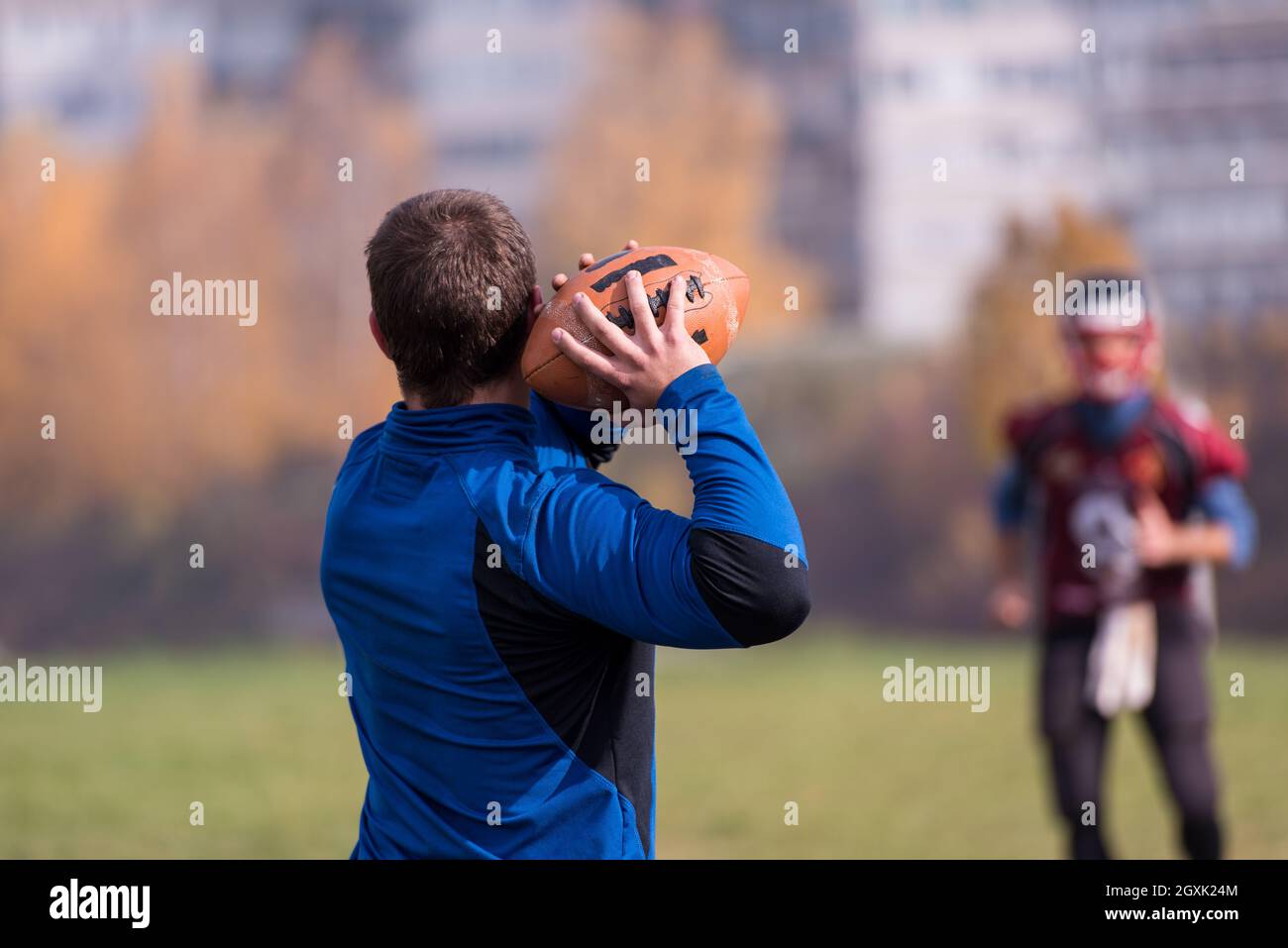 Team coach throwing the ball into the group of young american football ...