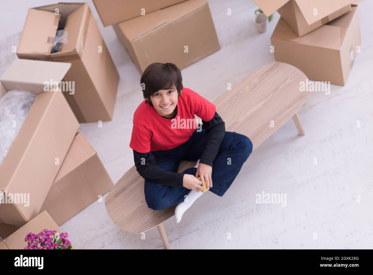 happy little boy sitting on the table with cardboard boxes around him ...