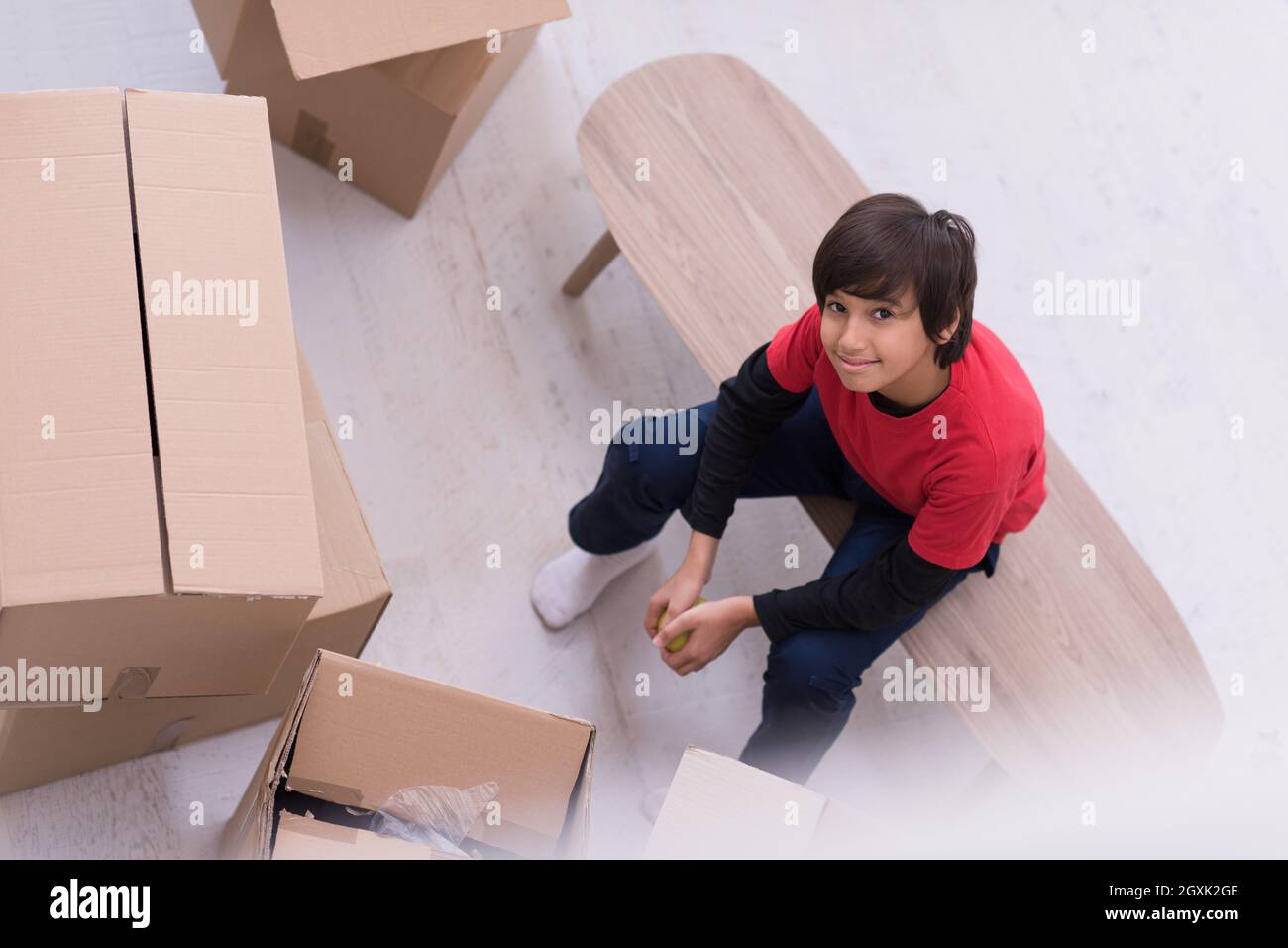 happy little boy sitting on the table with cardboard boxes around him ...
