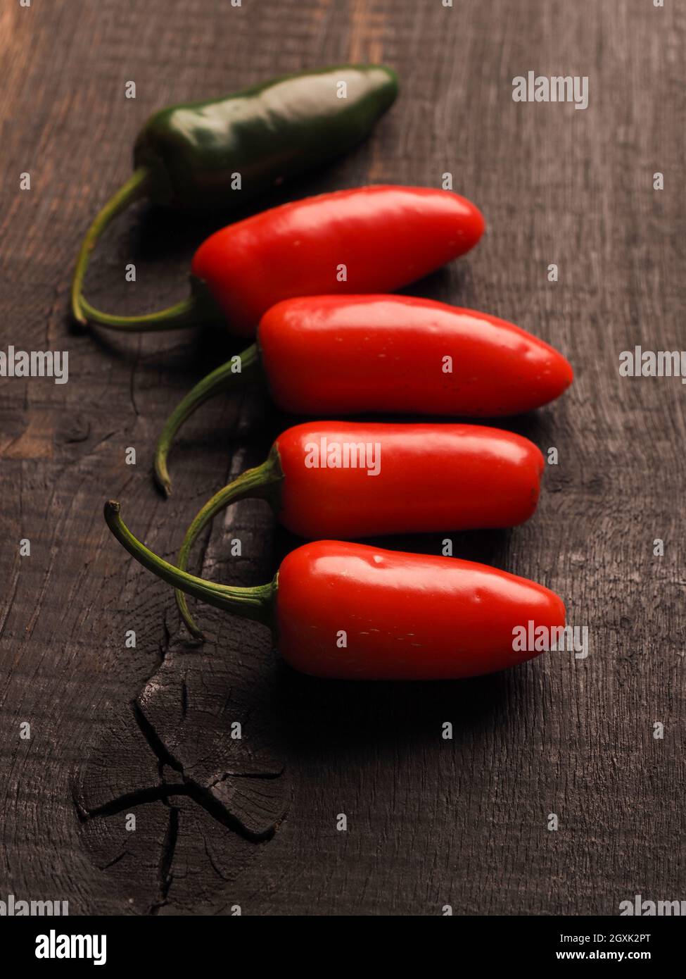 Five freshly harvested homegrown hot peppers on a rustic kitchen table ...