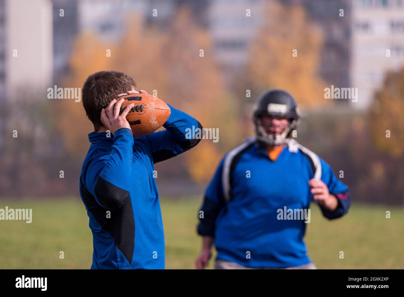 Team coach throwing the ball into the group of young american football ...