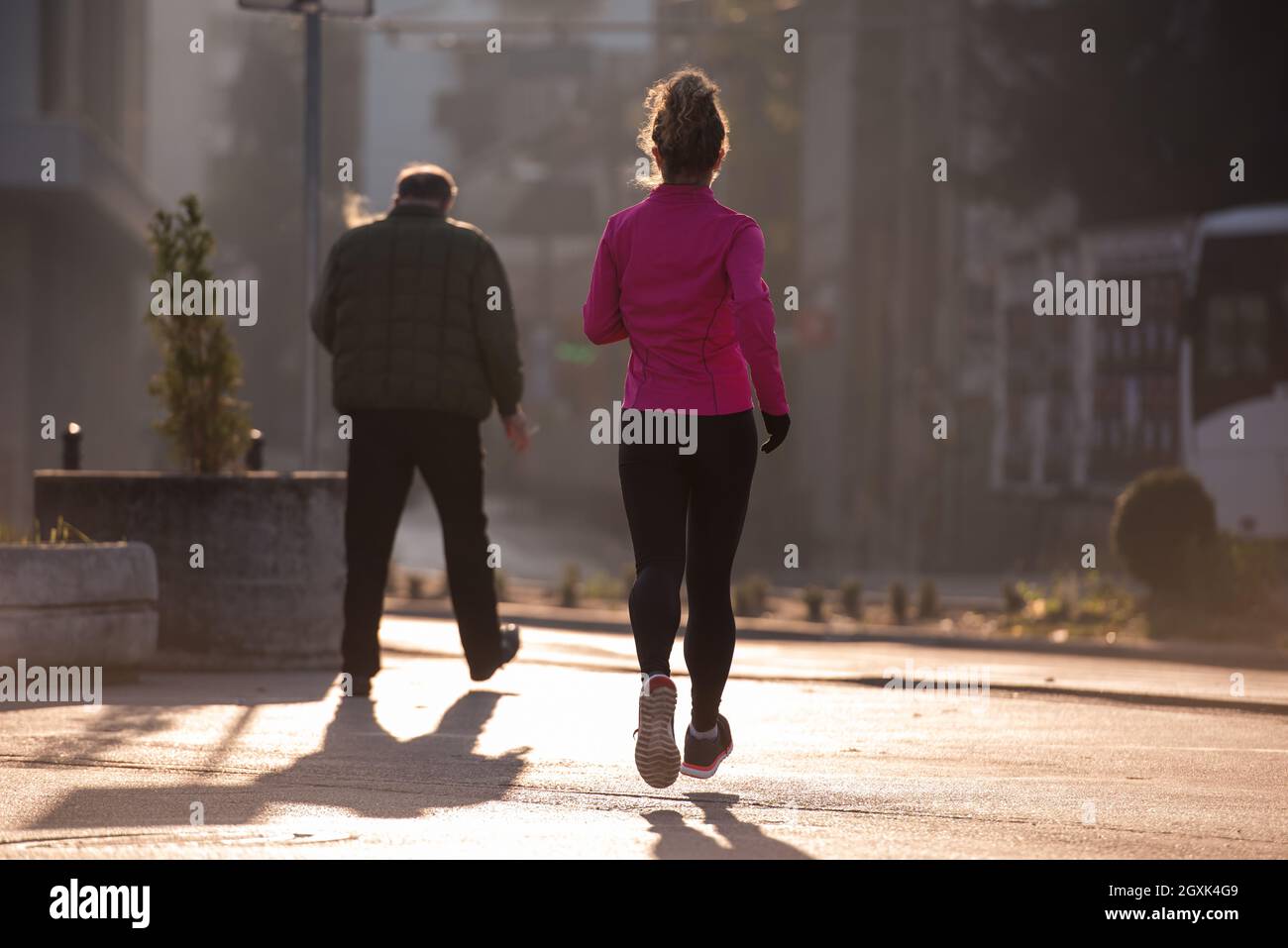 sporty woman running on sidewalk at early morning jogging with city ...
