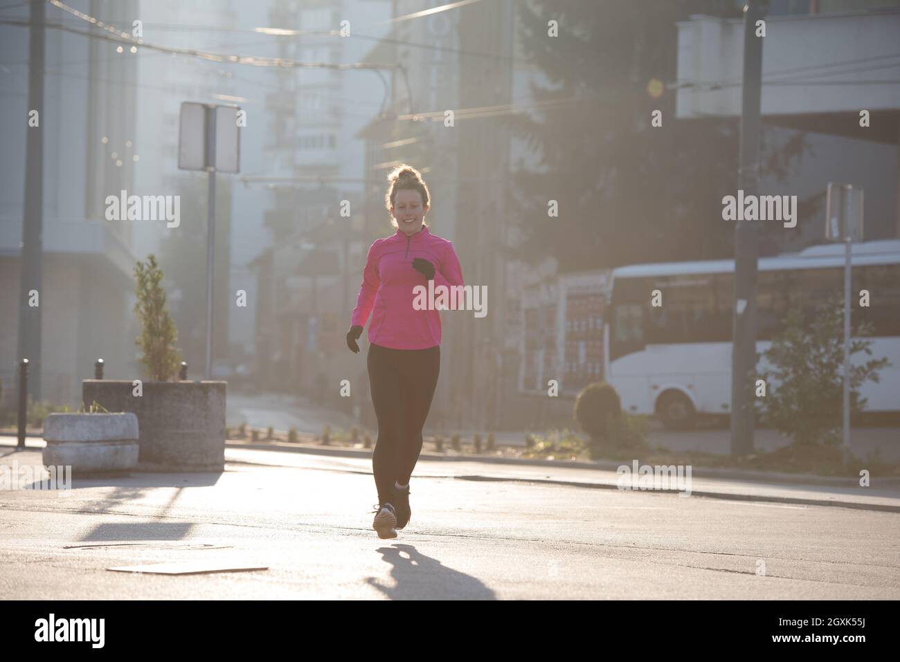 sporty woman running on sidewalk at early morning jogging with city ...