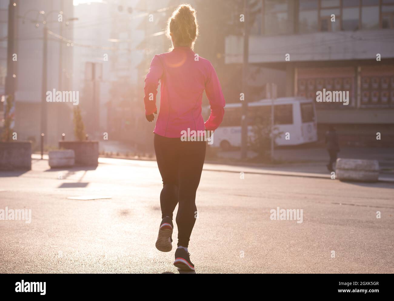 sporty woman running on sidewalk at early morning jogging with city ...
