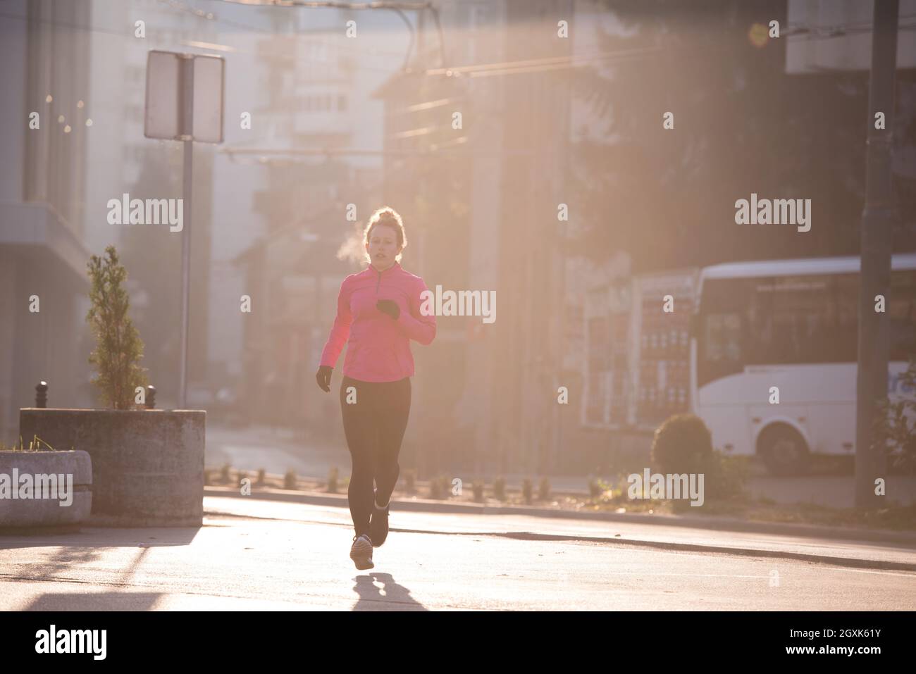 sporty woman running on sidewalk at early morning jogging with city ...