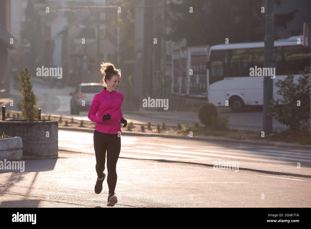 sporty woman running on sidewalk at early morning jogging with city ...