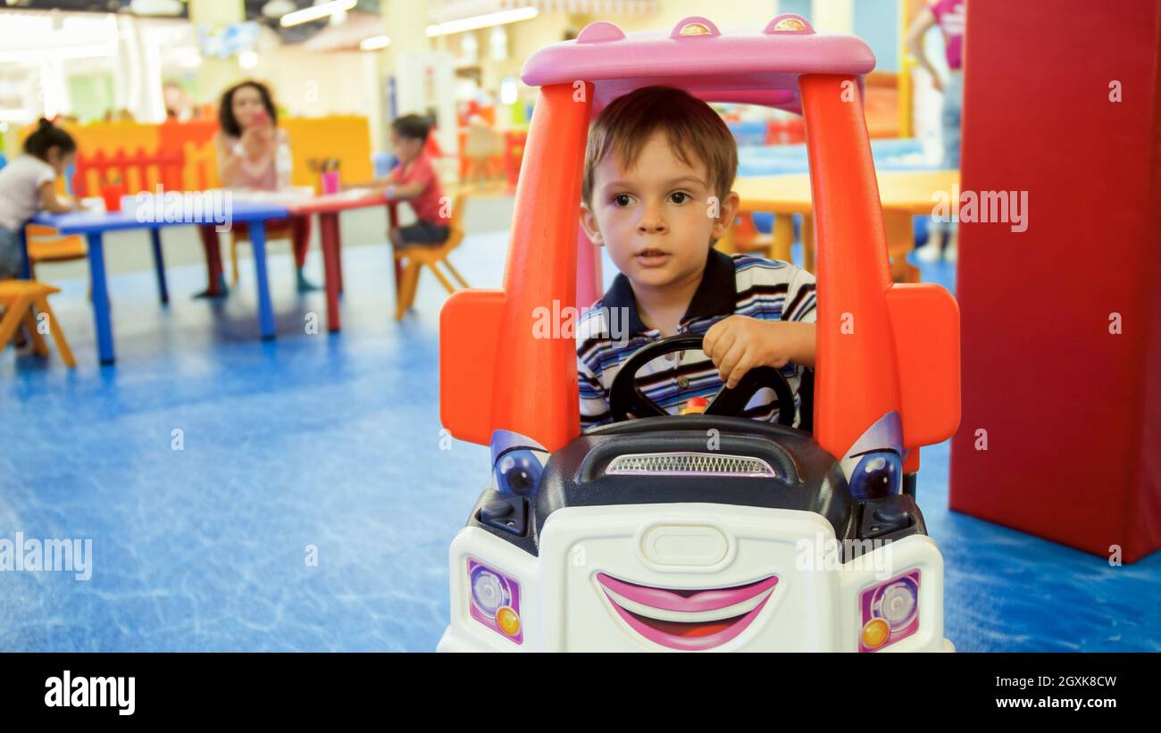 Portrait of little toddler boy riding in toy shopping cart for children ...