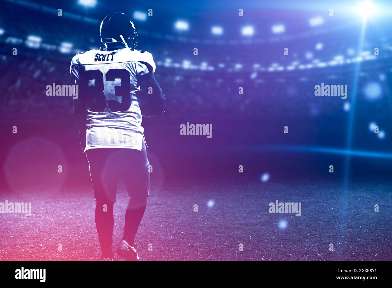 rear view of young confident American football player on field at night ...