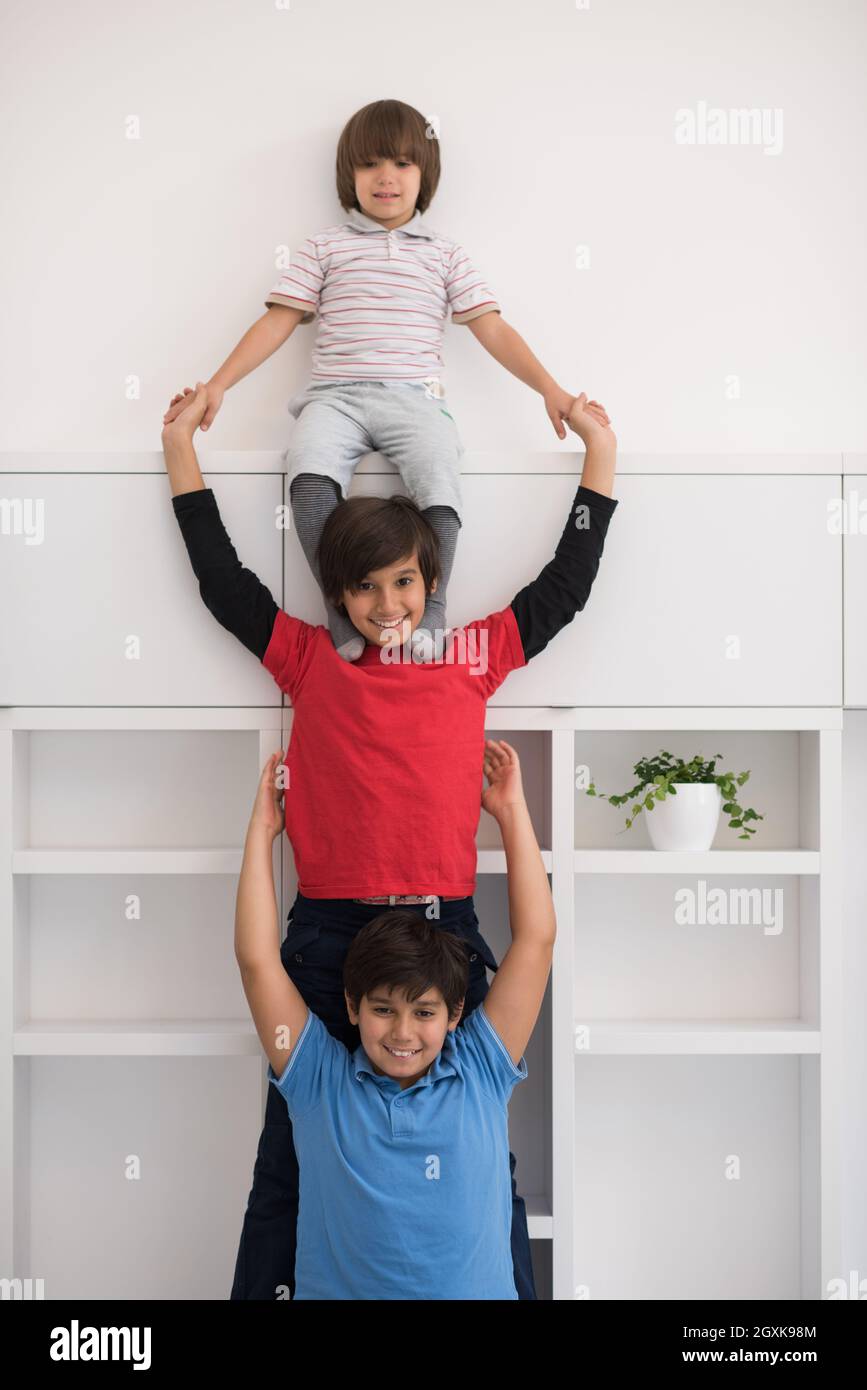 happy young boys having fun and posing line up piggyback in new modern ...