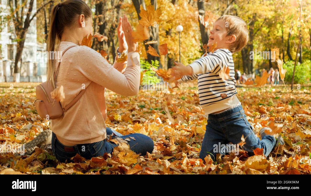 Little boy throwing fallen autumn leaves at his mother at park Stock ...