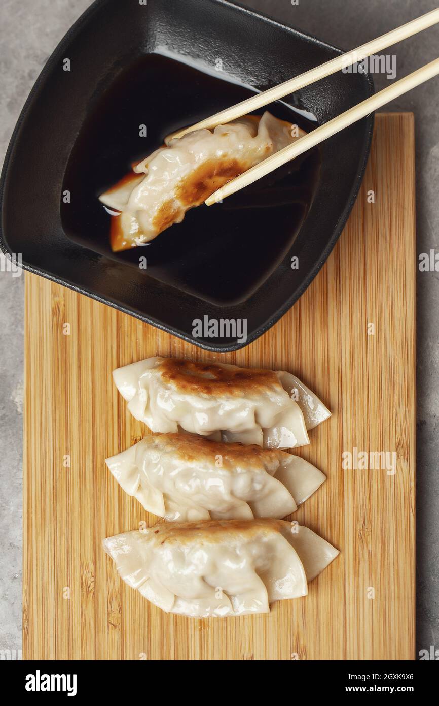 Gyoza or dumplings snack with soy sauce on wood board and grey clay ...