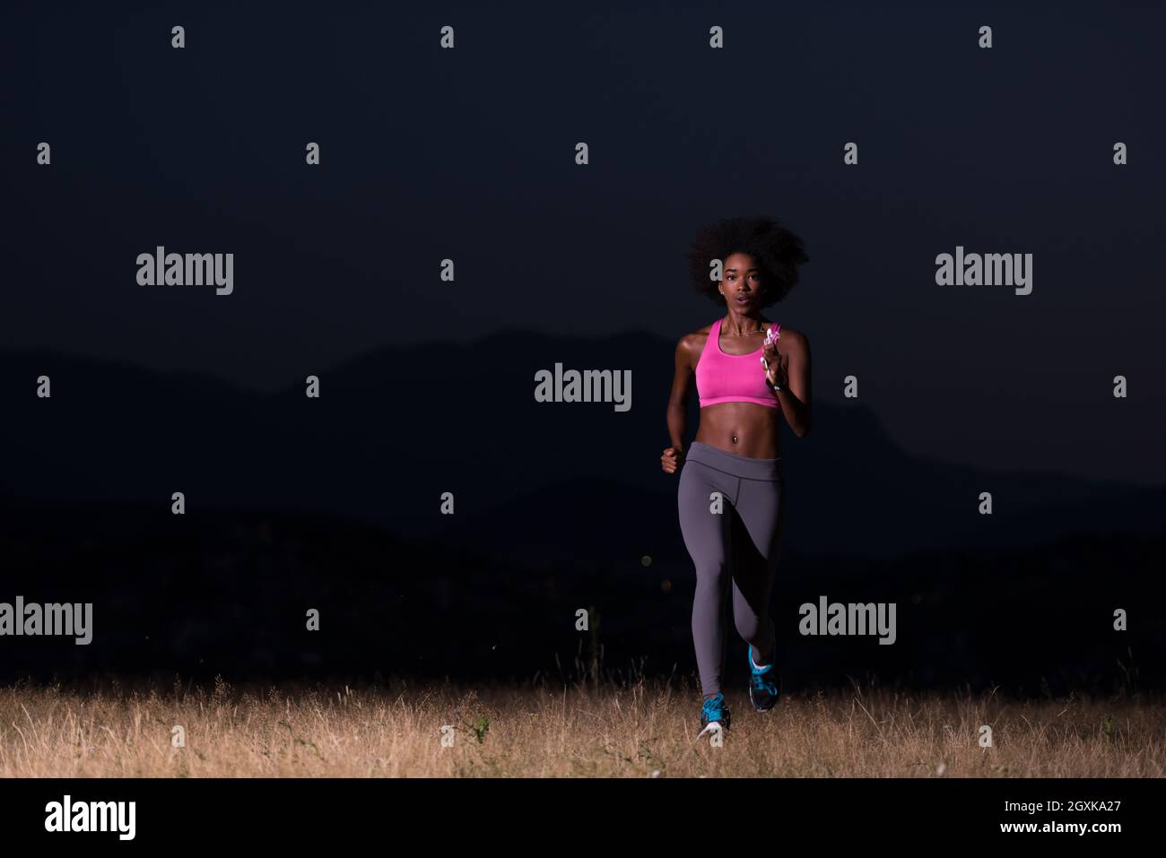 young African american woman runner with headphones jogging outdoors in ...