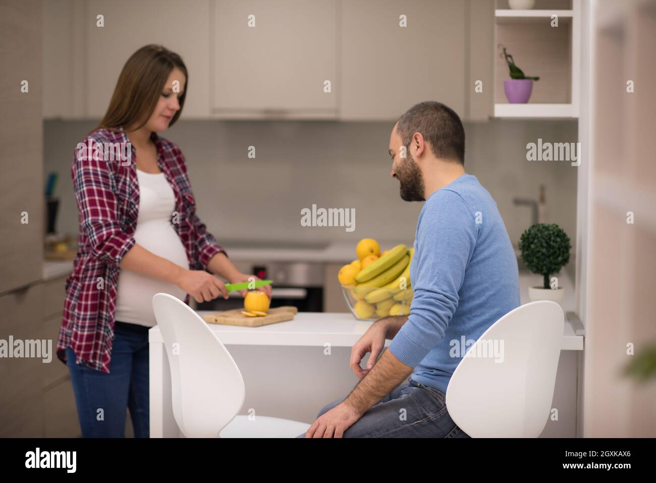 young pregnant couple cooking food fruit lemon juice at kitchen ...