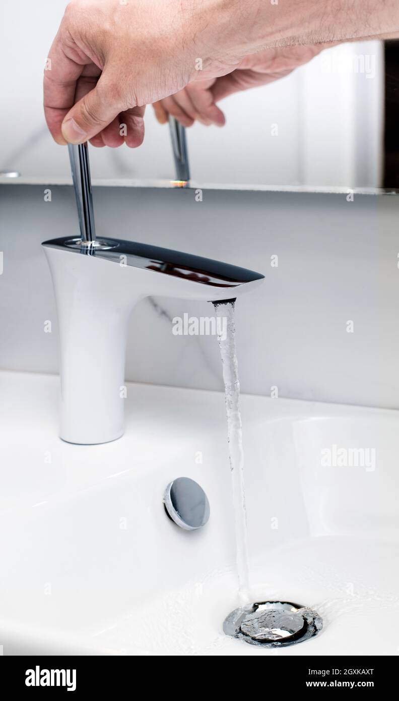 The hand opens the tap to let the water flow into the sink Stock Photo ...
