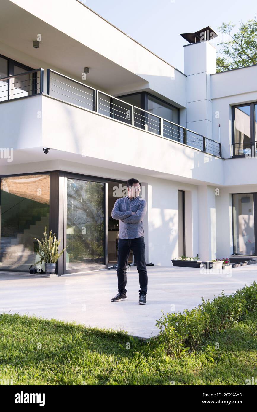 portrait of a young handsome successful man in front of his luxury home ...
