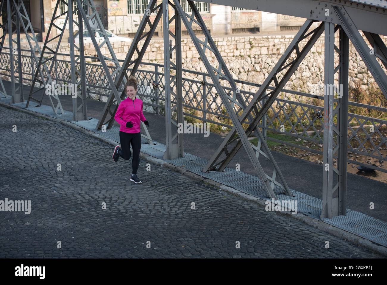 sporty woman running on sidewalk at early morning jogging with city ...
