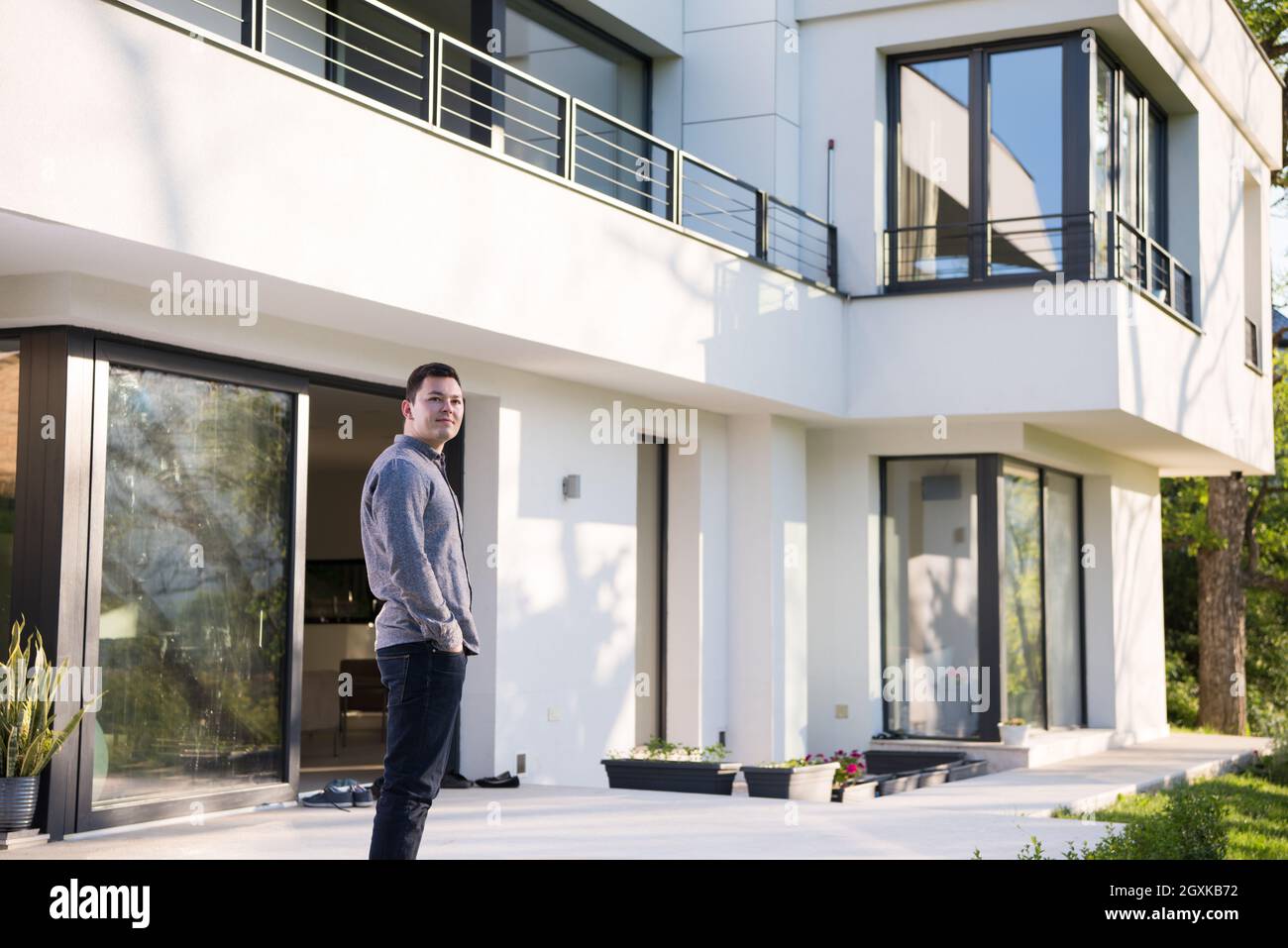 portrait of a young handsome successful man in front of his luxury home ...