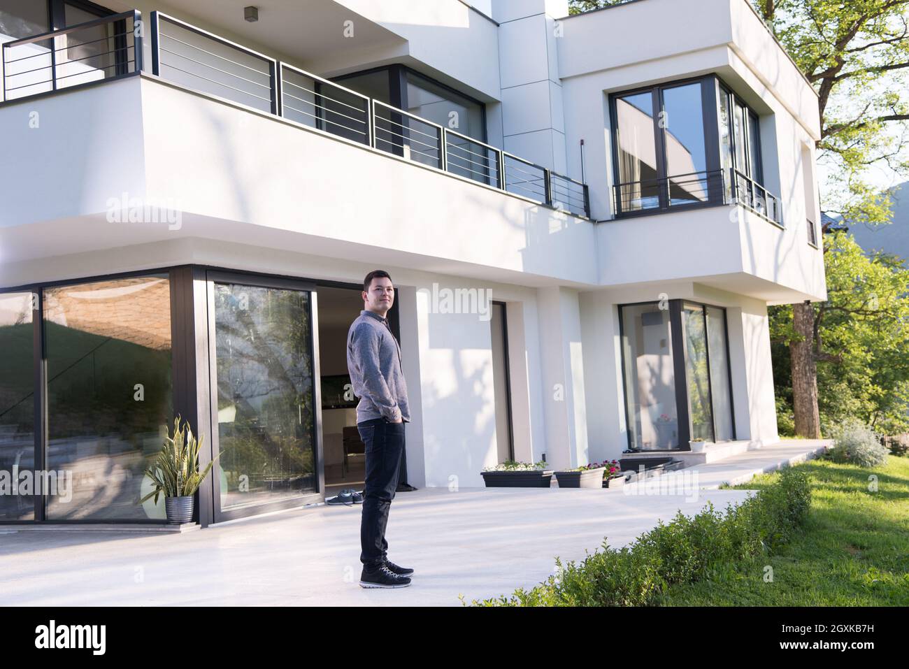 portrait of a young handsome successful man in front of his luxury home ...