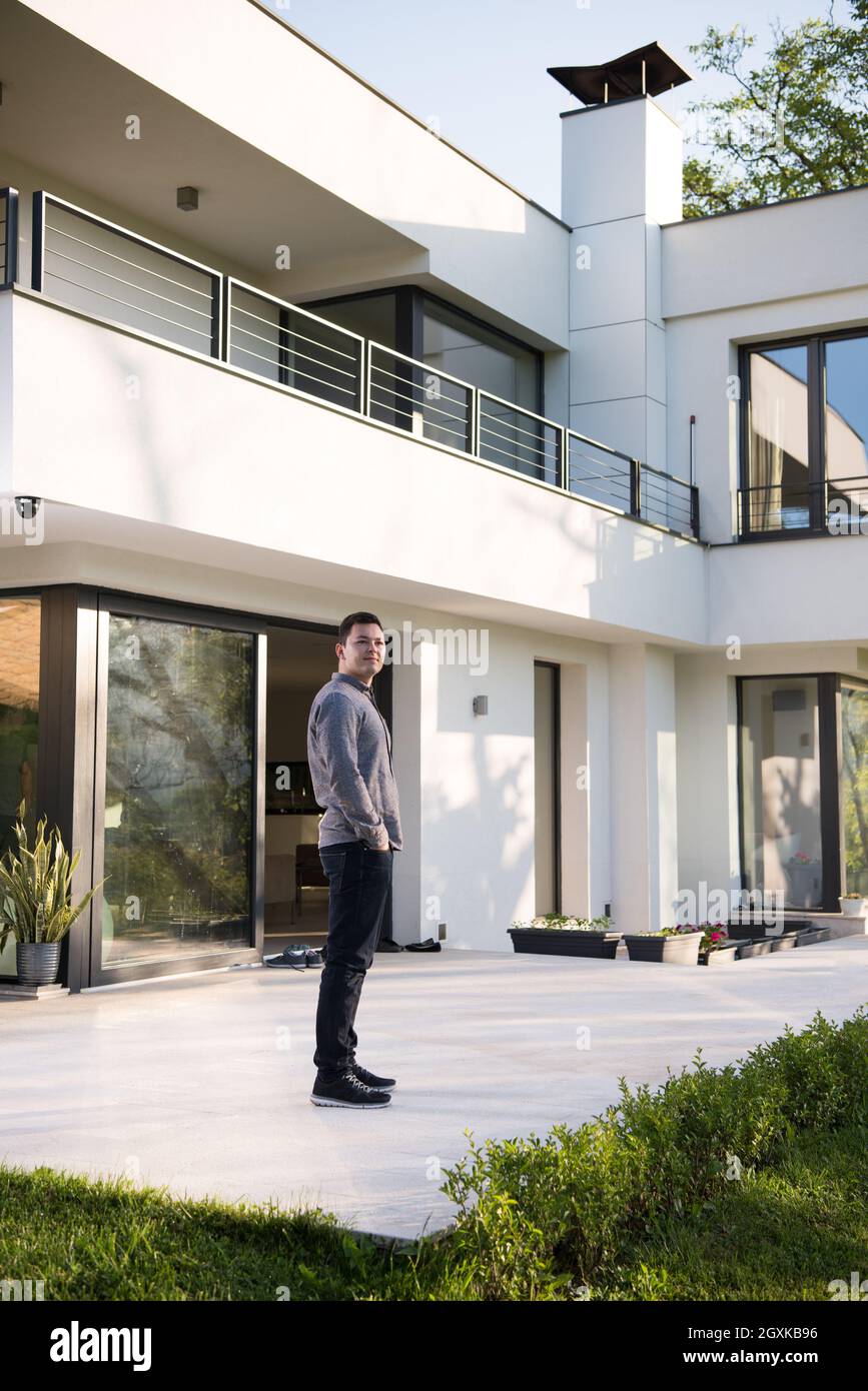 portrait of a young handsome successful man in front of his luxury home ...