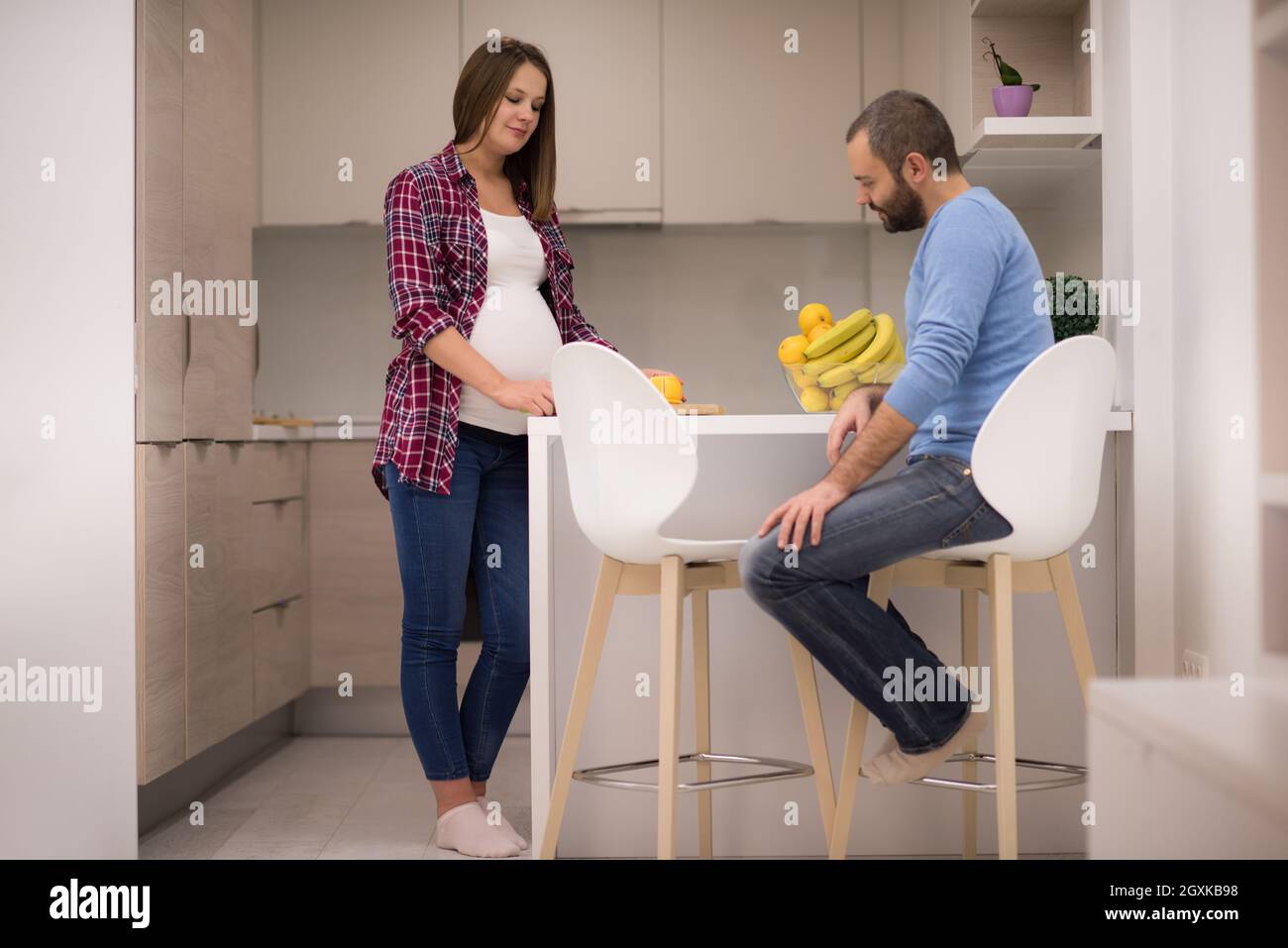 young pregnant couple cooking food fruit lemon juice at kitchen ...