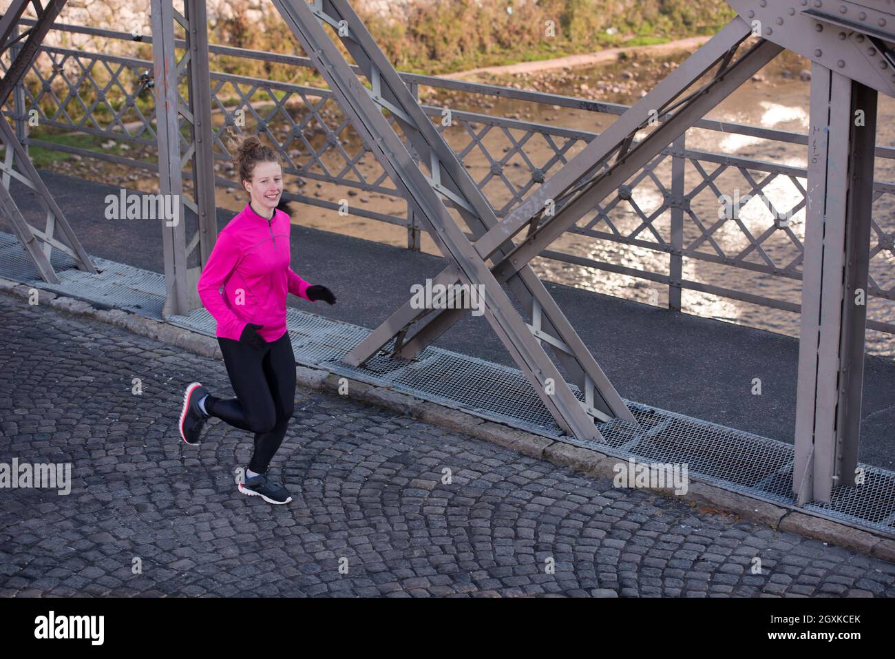 sporty woman running on sidewalk at early morning jogging with city ...