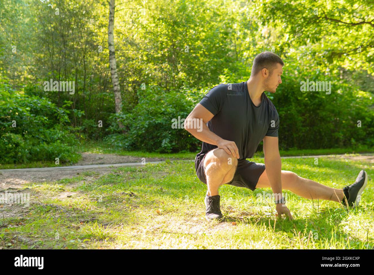 A young enduring athletic athlete is doing stretching in the forest ...