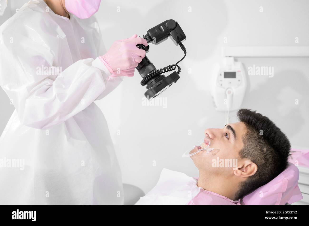Dentist with camera making shots of beautiful young patient's smile ...