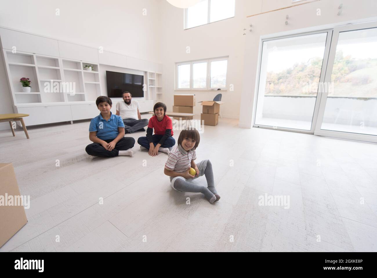 portrait of happy young boys with their dad sitting on the floor in a ...