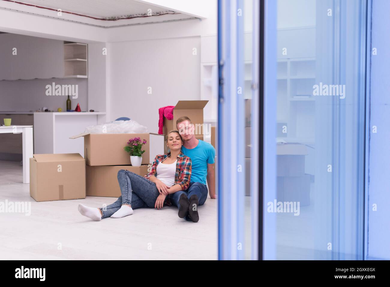 Relaxing in new house. Cheerful young couple sitting on the floor while ...