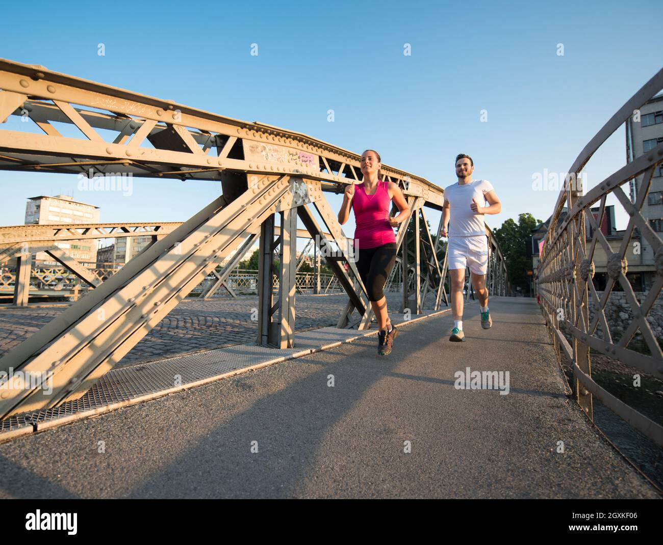 urban sports, healthy young couple jogging across the bridge in the ...