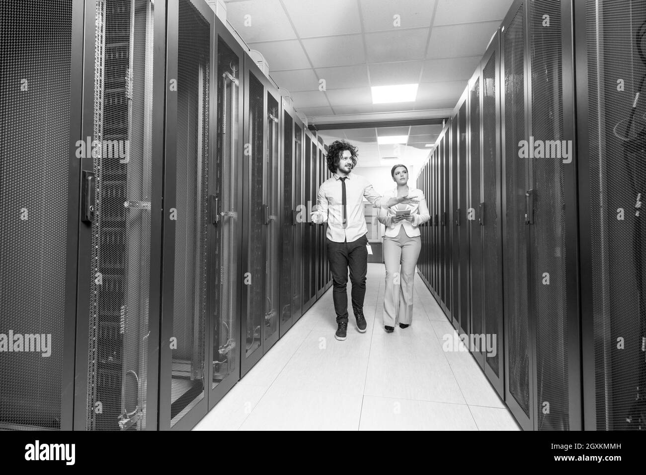 Young IT engineer showing working data center server room to female ...