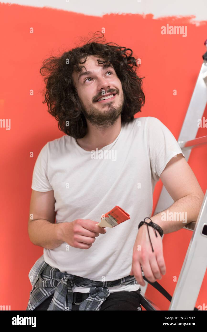 Portrait of a beautiful young man with funny hair and brush over color ...