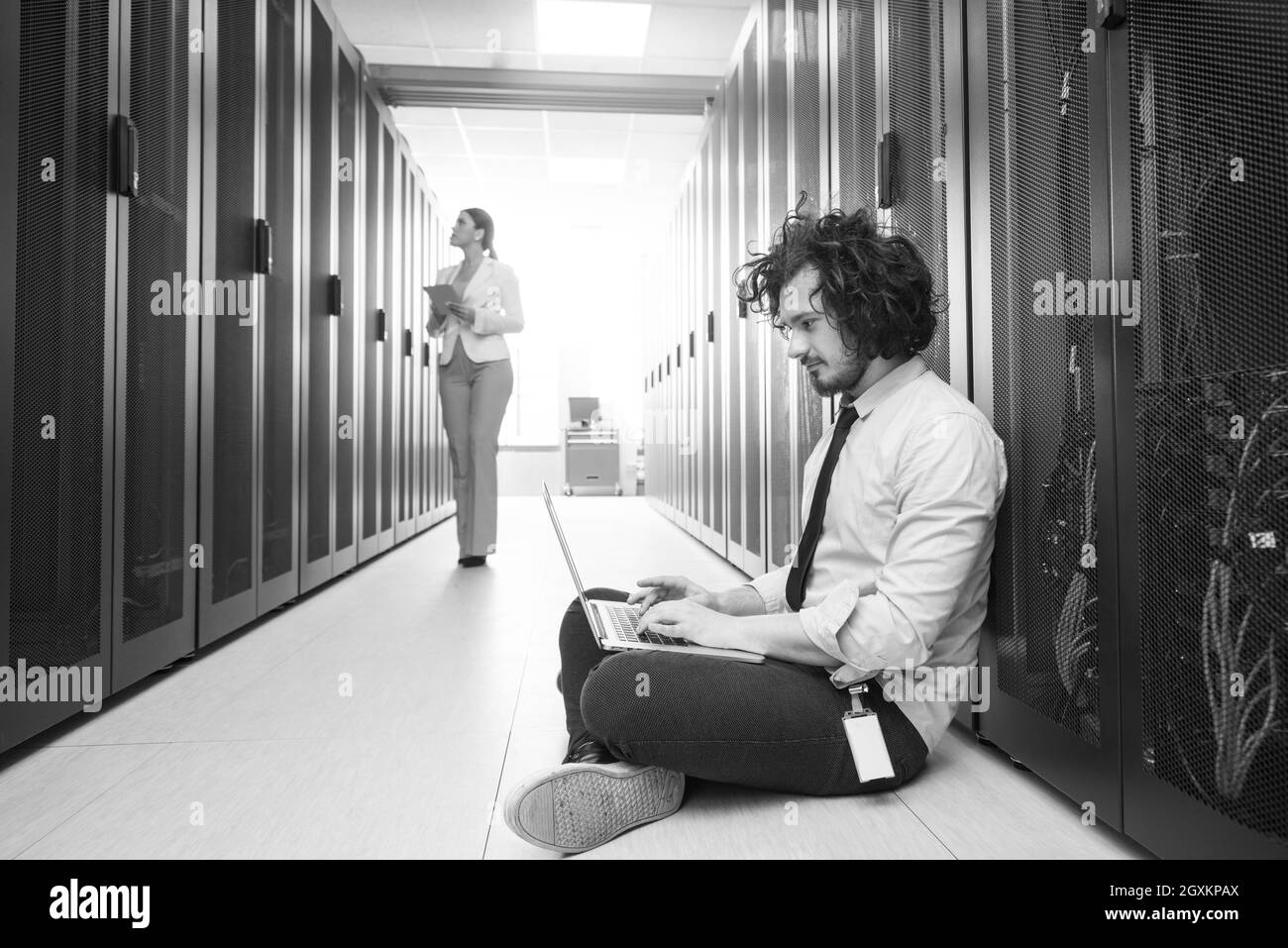 Team of young technicians working together on servers at the data center using laptop and tablet ...