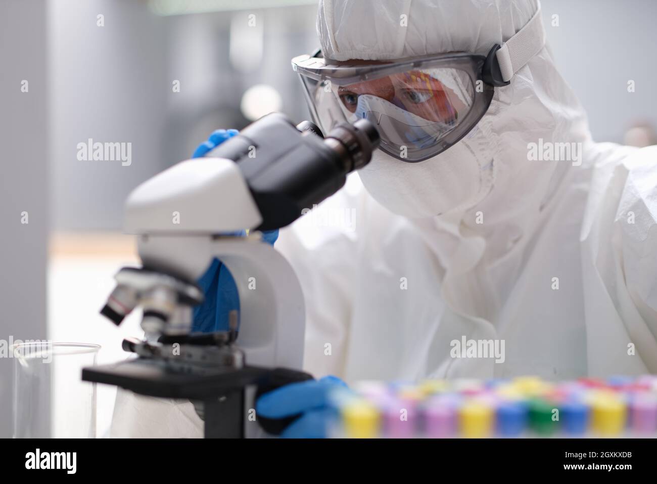 Scientist chemist in protective anti-plague suit looking through ...
