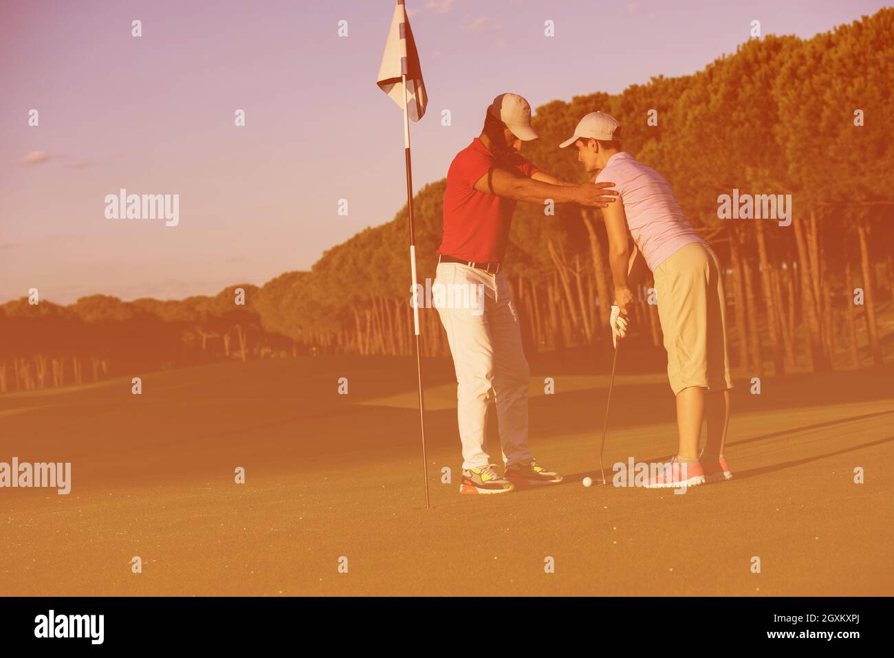 male golf instructor teaching female golf player, personal trainer ...
