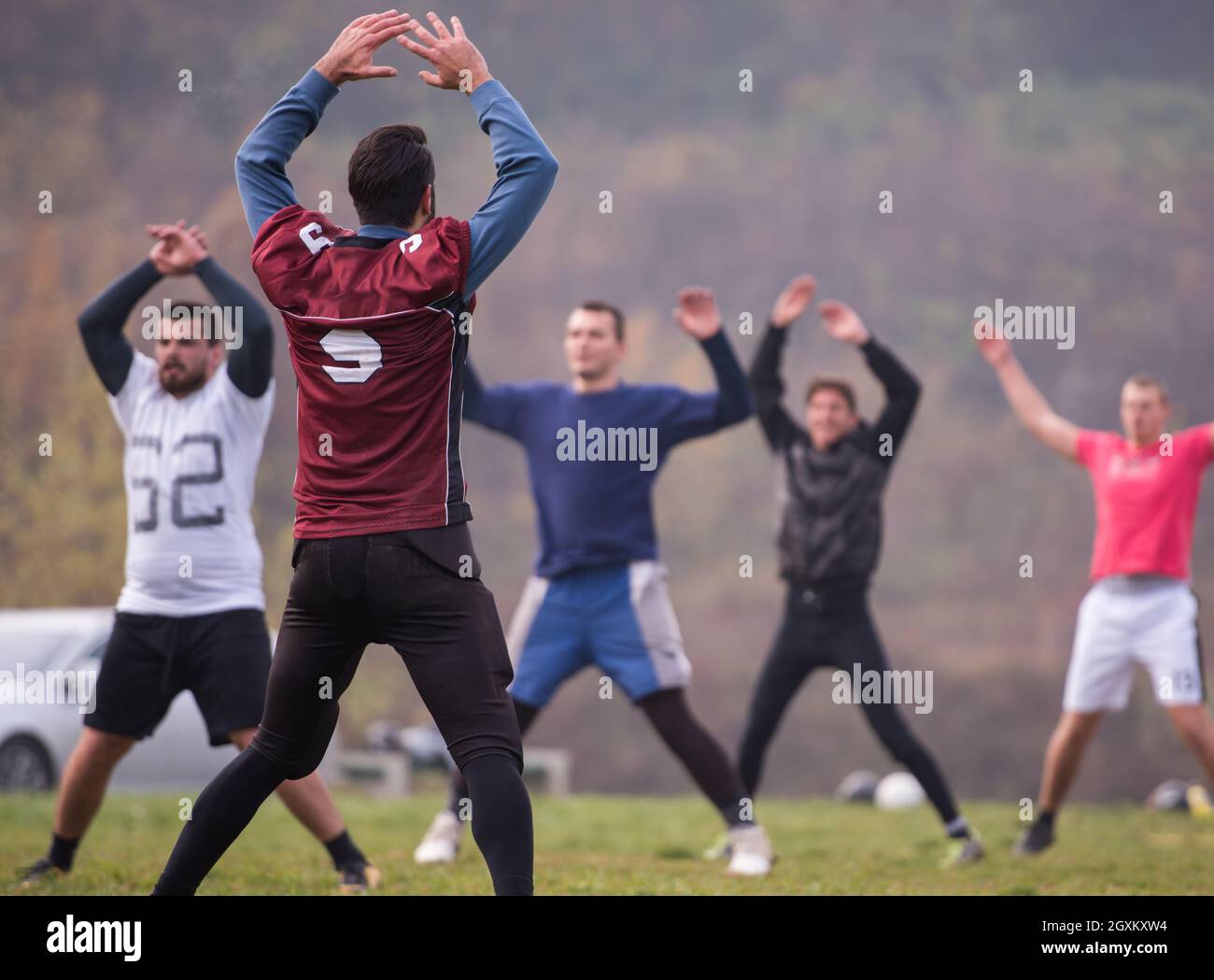 group of young american football players stretching and warming up ...