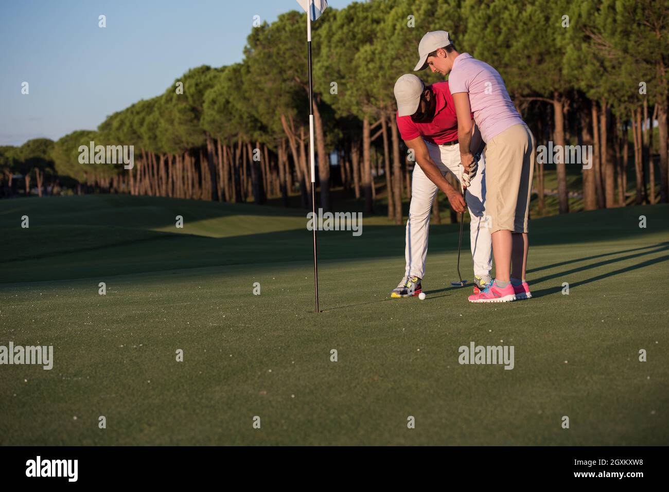 male golf instructor teaching female golf player, personal trainer ...