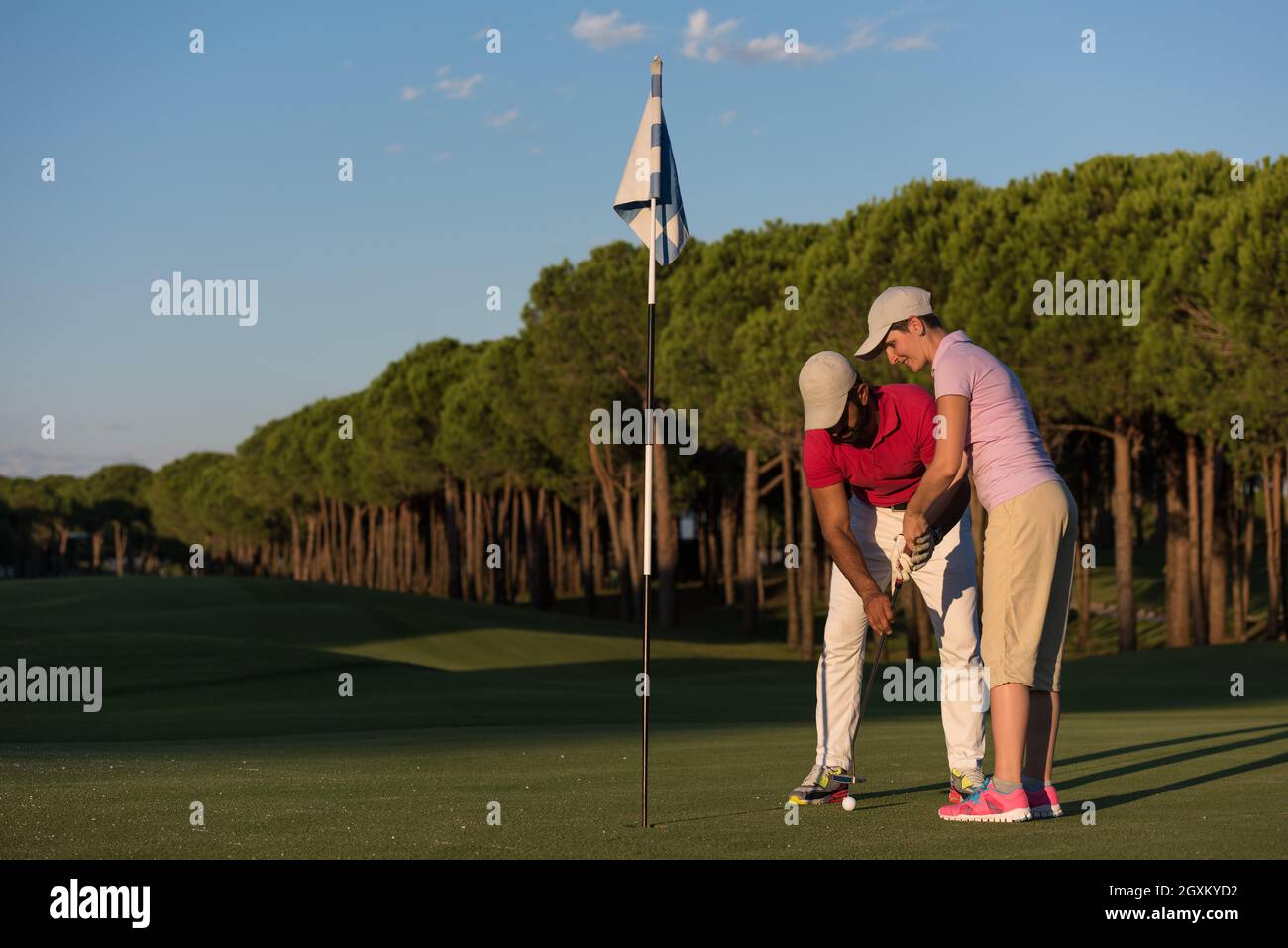 male golf instructor teaching female golf player, personal trainer ...